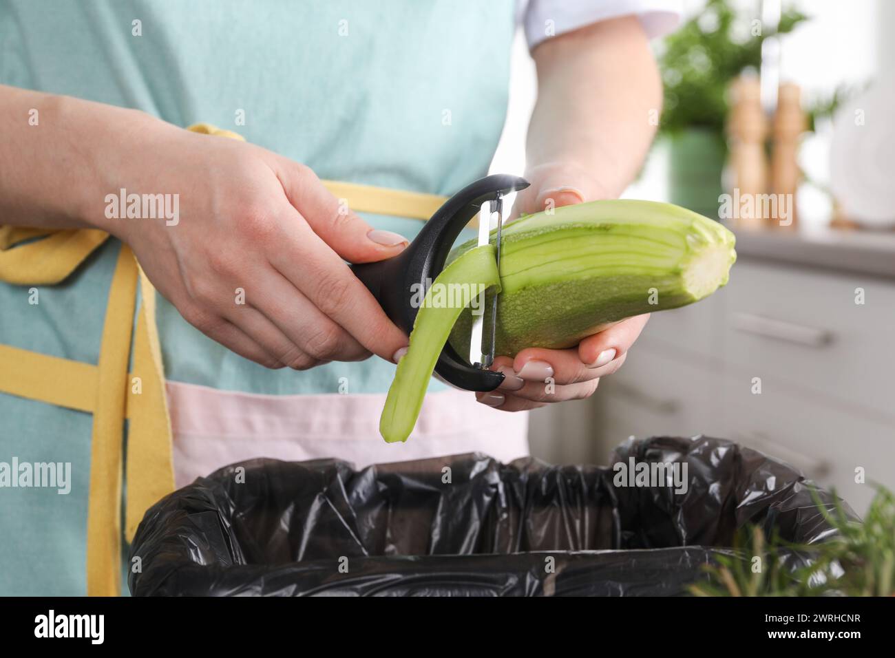 Woman peeling fresh zucchini above garbage bin indoors, closeup Stock ...