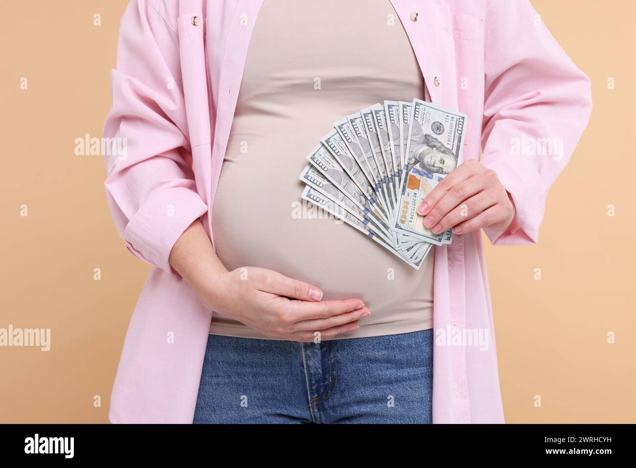 Surrogate mother. Pregnant woman with dollar banknotes on beige ...