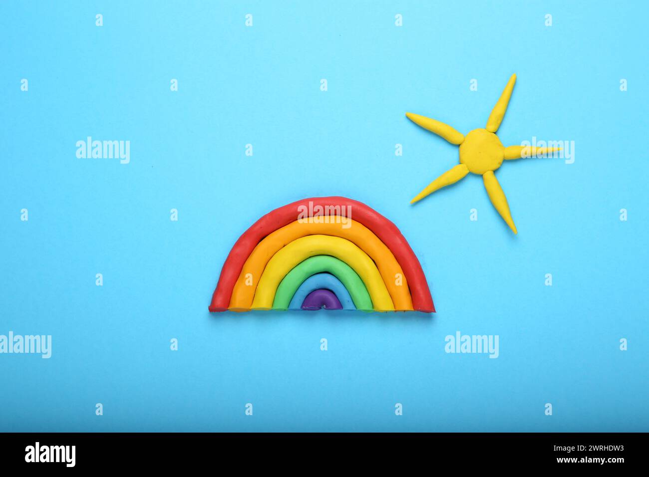 Rainbow and sun made of plasticine on light blue background, top view ...