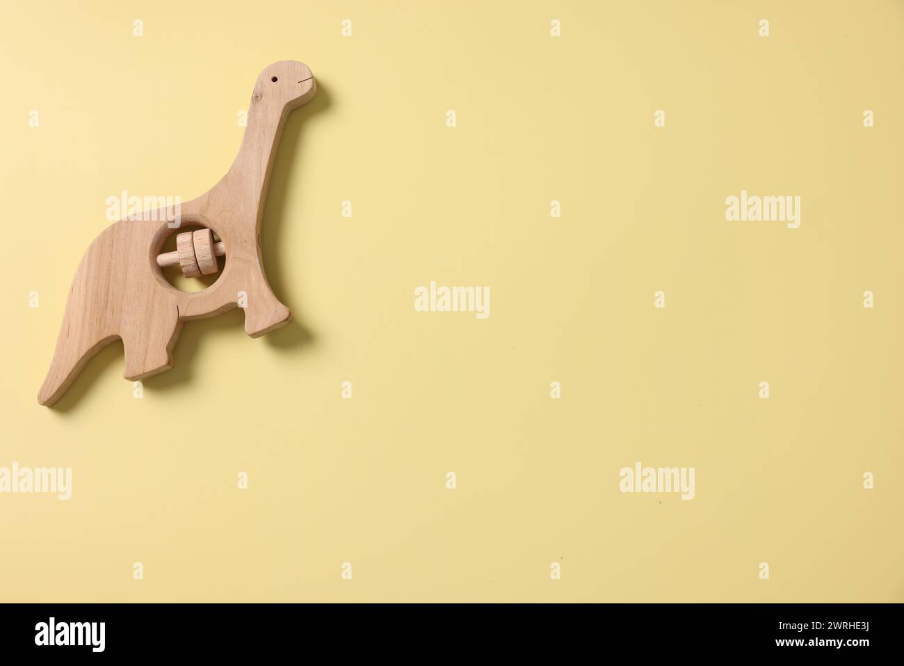 Baby accessory. Wooden rattle on yellow background, top view. Space for ...