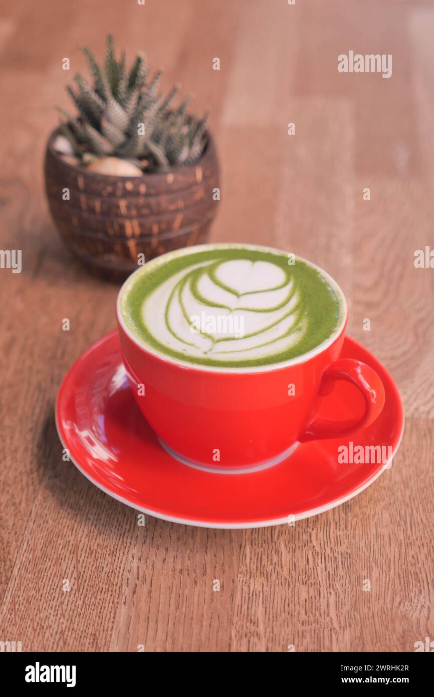 matcha latte in a red color cup on table Stock Photo - Alamy