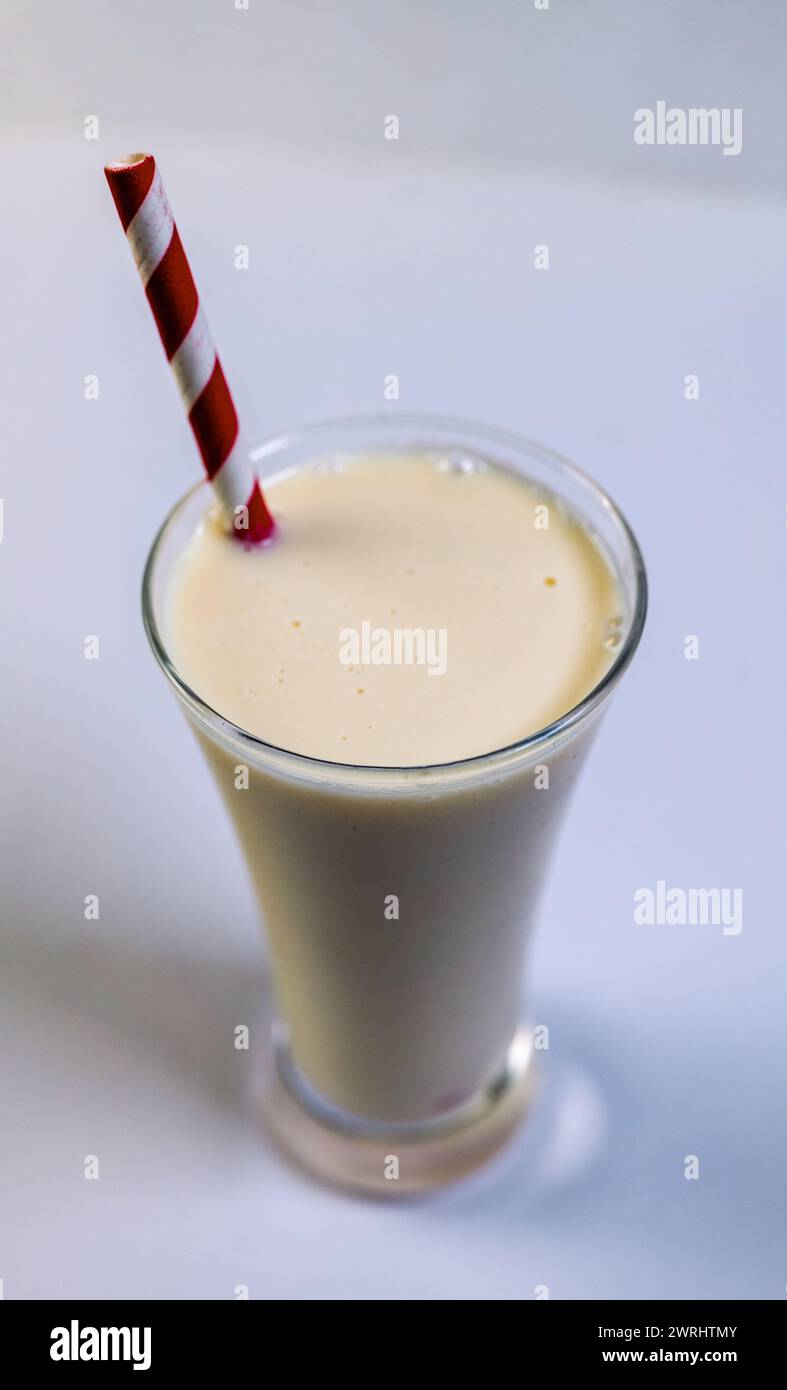 A tempting milkshake in a glass with a colorful striped straw, isolated ...