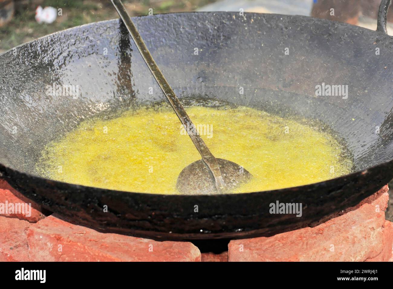 A pot of hot oil stands on traditional bricks, ready for frying food ...