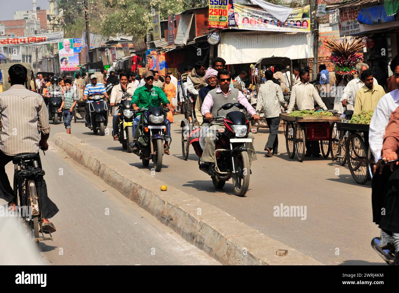 A busy street scene with motorbikes and cyclists in a city, Varanasi ...
