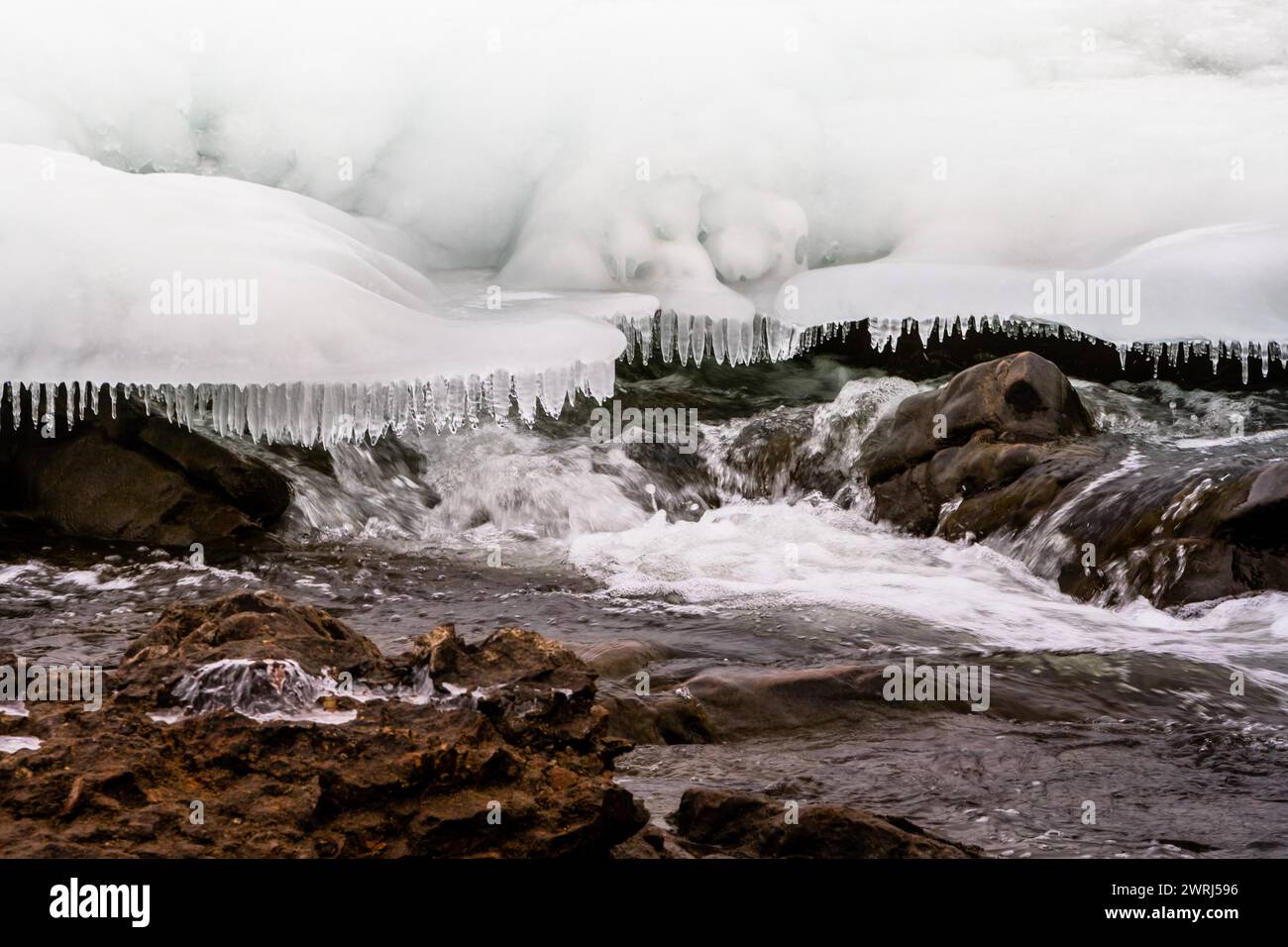 Packed snow and ice with ice-cycles that look like teeth over rapidly ...