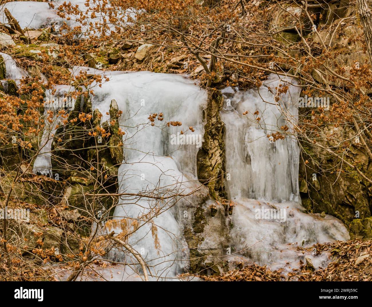 Frozen waterfall on side of mountain with granite boulders behind a ...