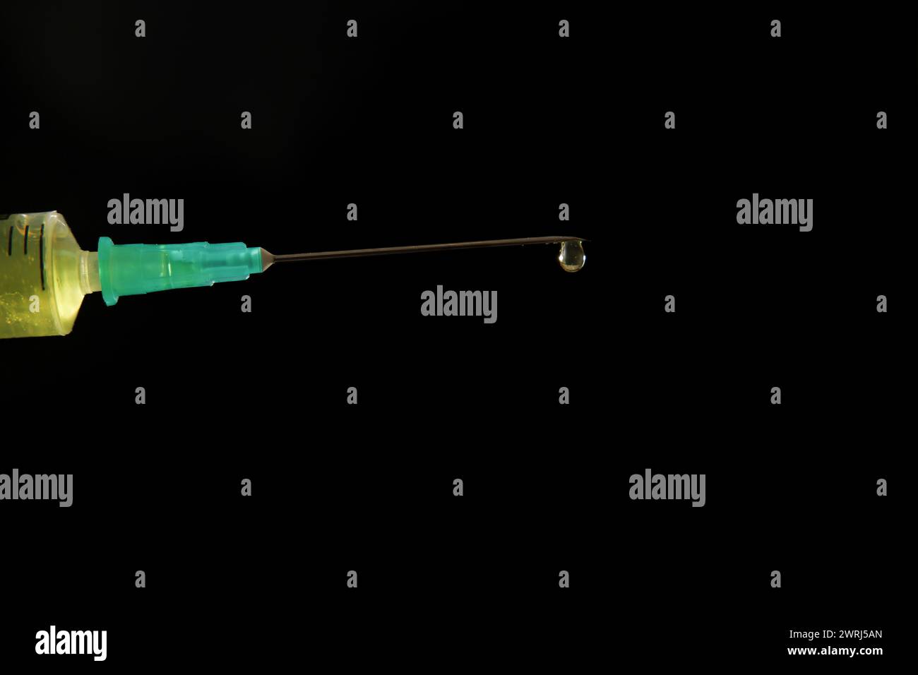 Syringe with needle with a drop of liquid coming out, isolated on black ...