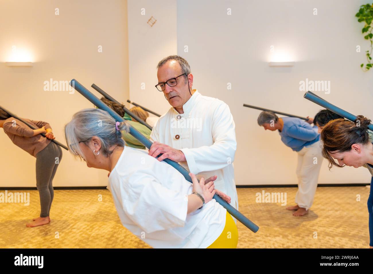 Qi gong class members using tube to stretch the back with the guidance ...
