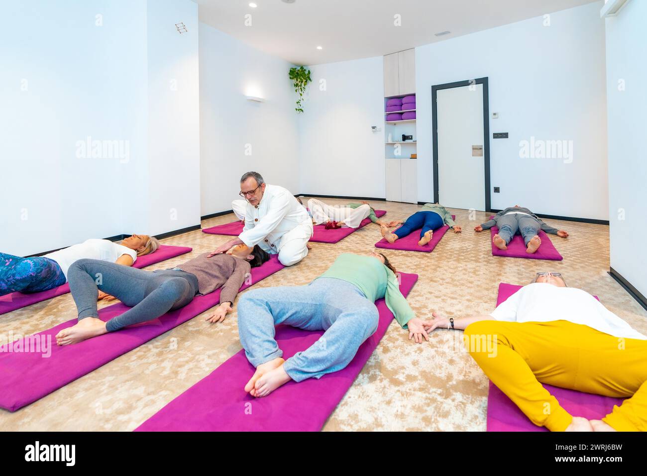 Women meditating during Qi gong class leaded by a instructor dressed ...