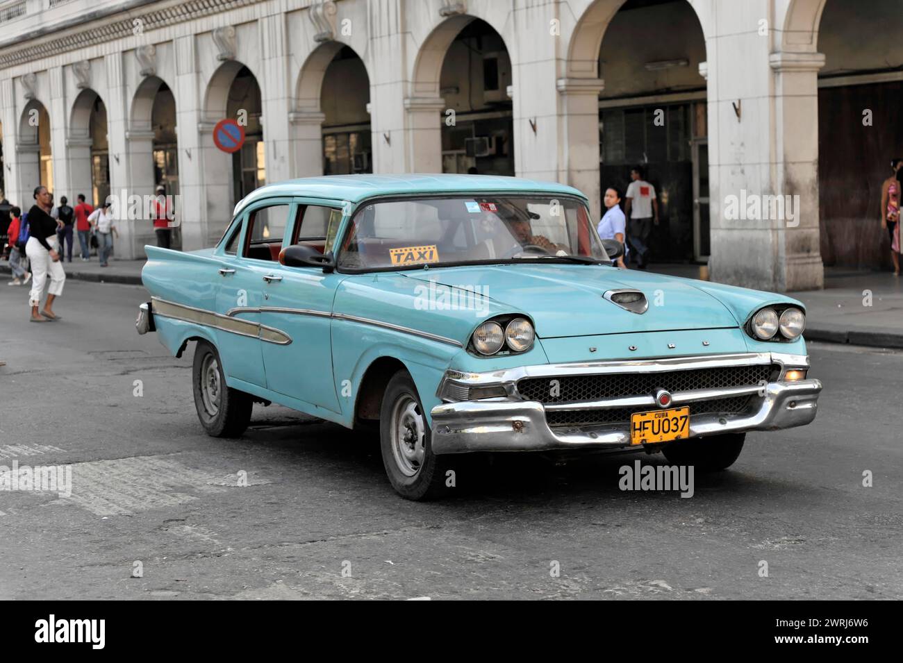 Light blue vintage car as a taxi on a busy street with passers-by in ...