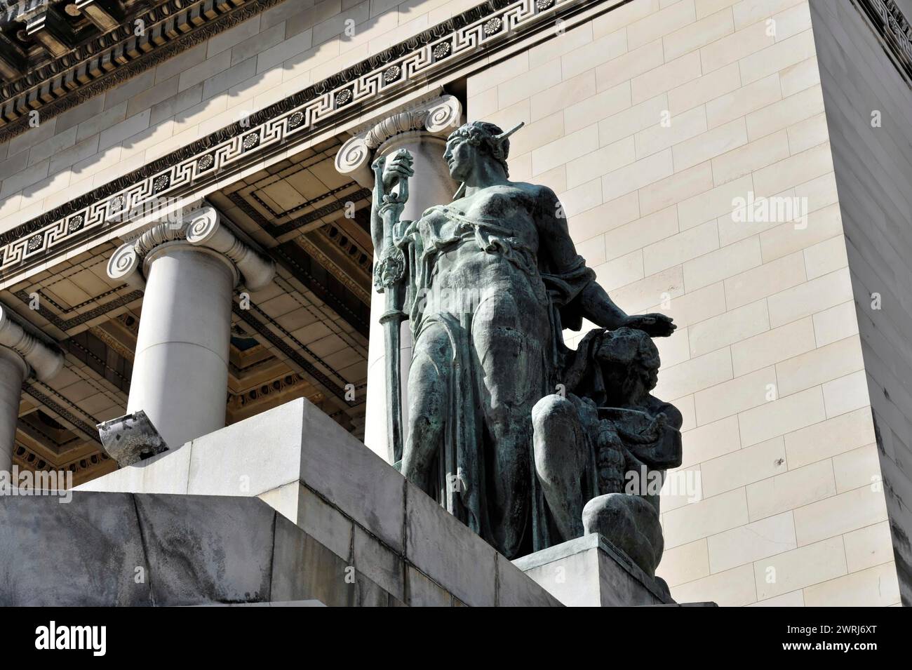 A statue with green patina in front of a historic building with ...
