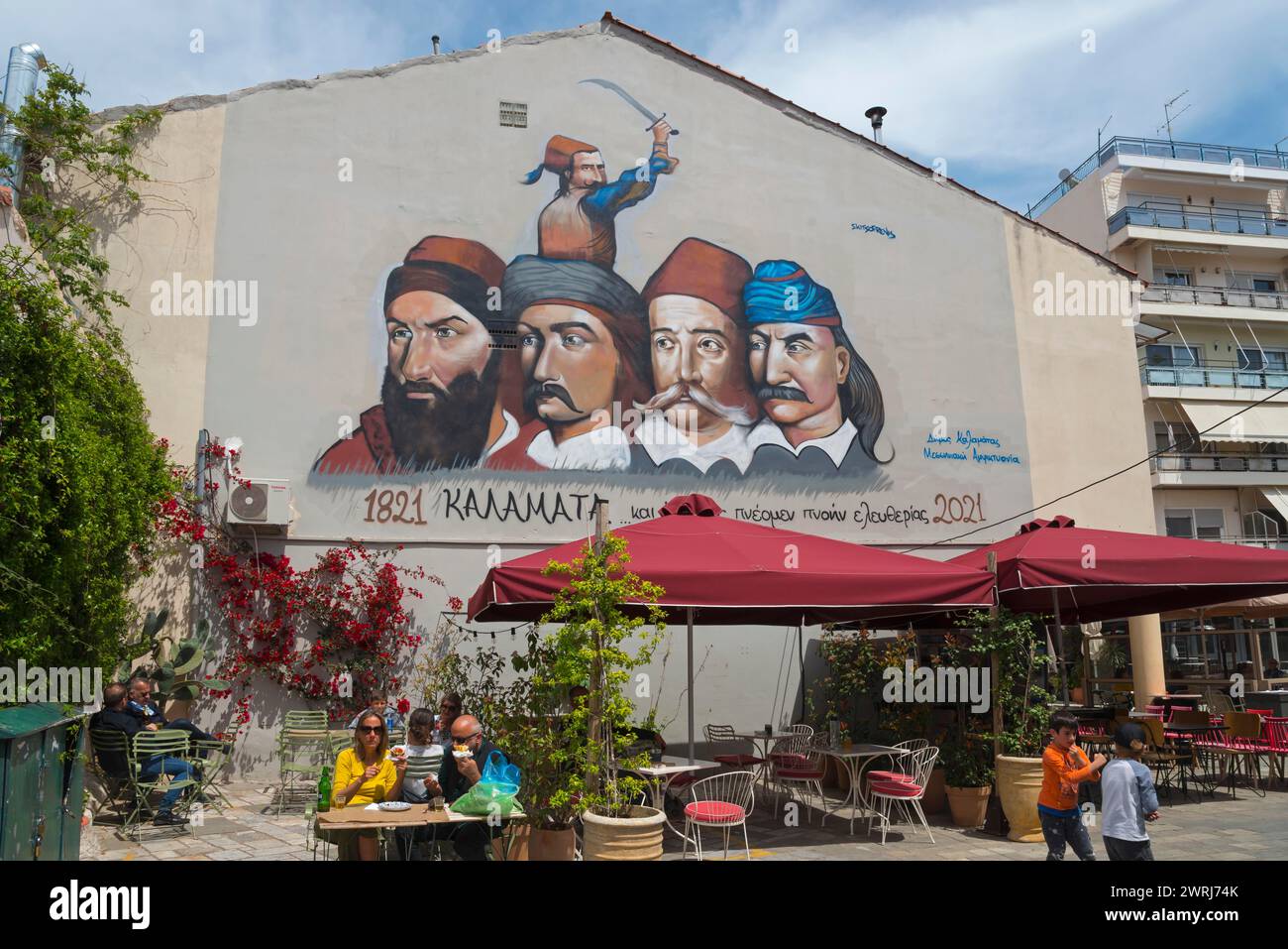 Large mural of historical figures above an urban cafe with passers-by ...