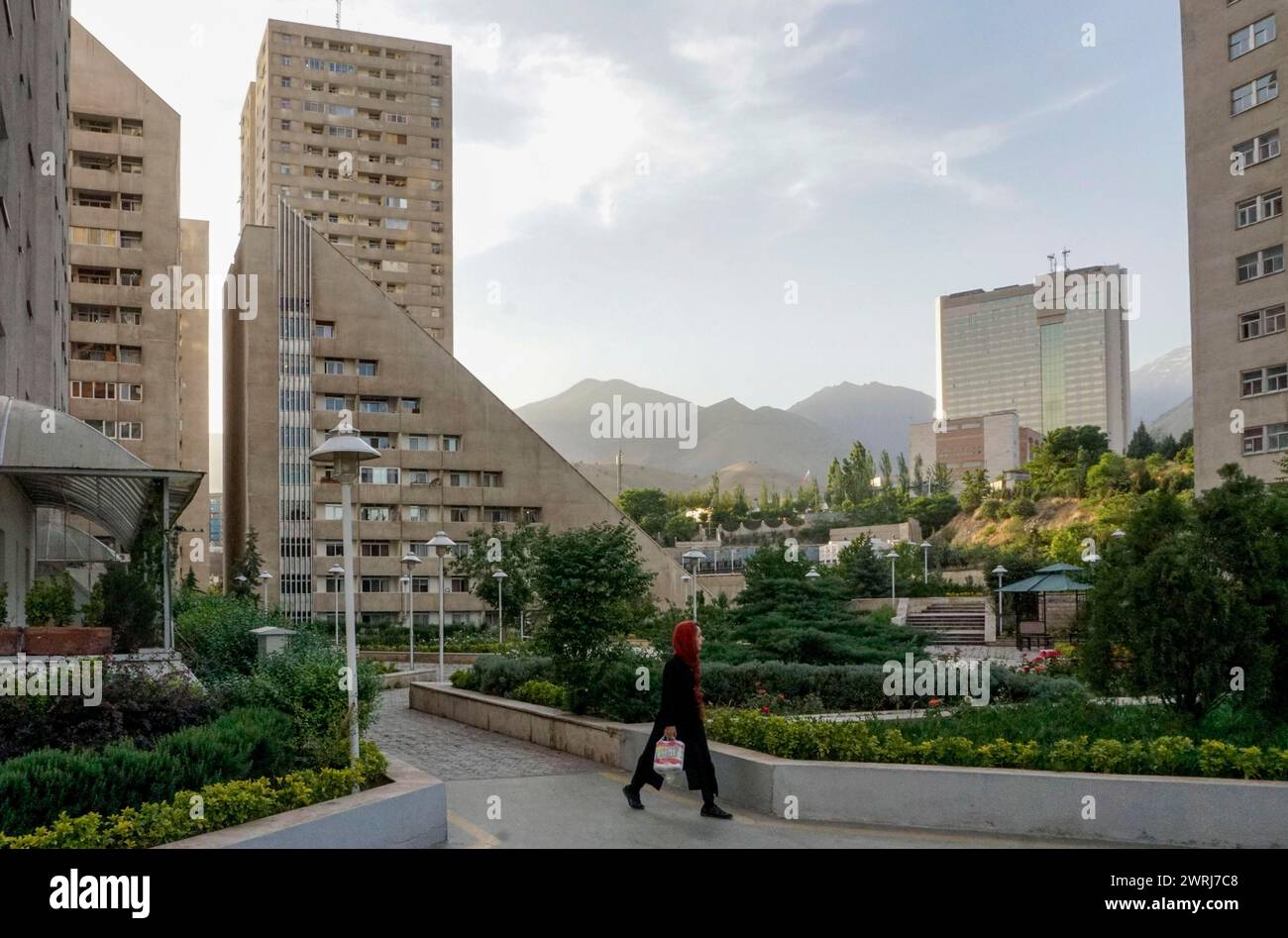 A woman walks through a modern housing estate with high-rise buildings ...