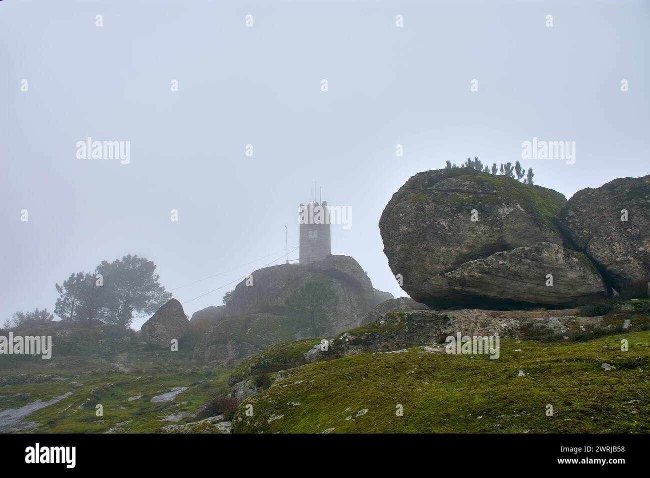 Castle clock tower among the rocks of Sortelha on a misty day and view ...
