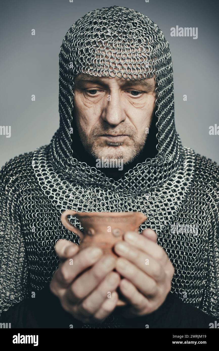 Medieval infantry armed man dressed in chain armor holding clay jug ...