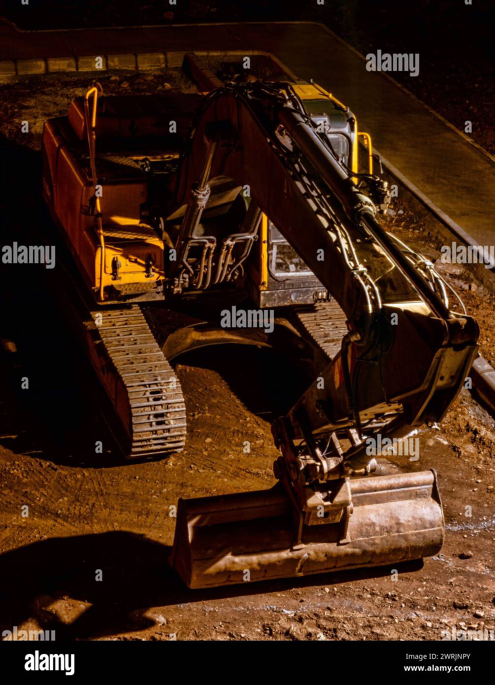 A yellow digger excavator parked during the night on a construction ...