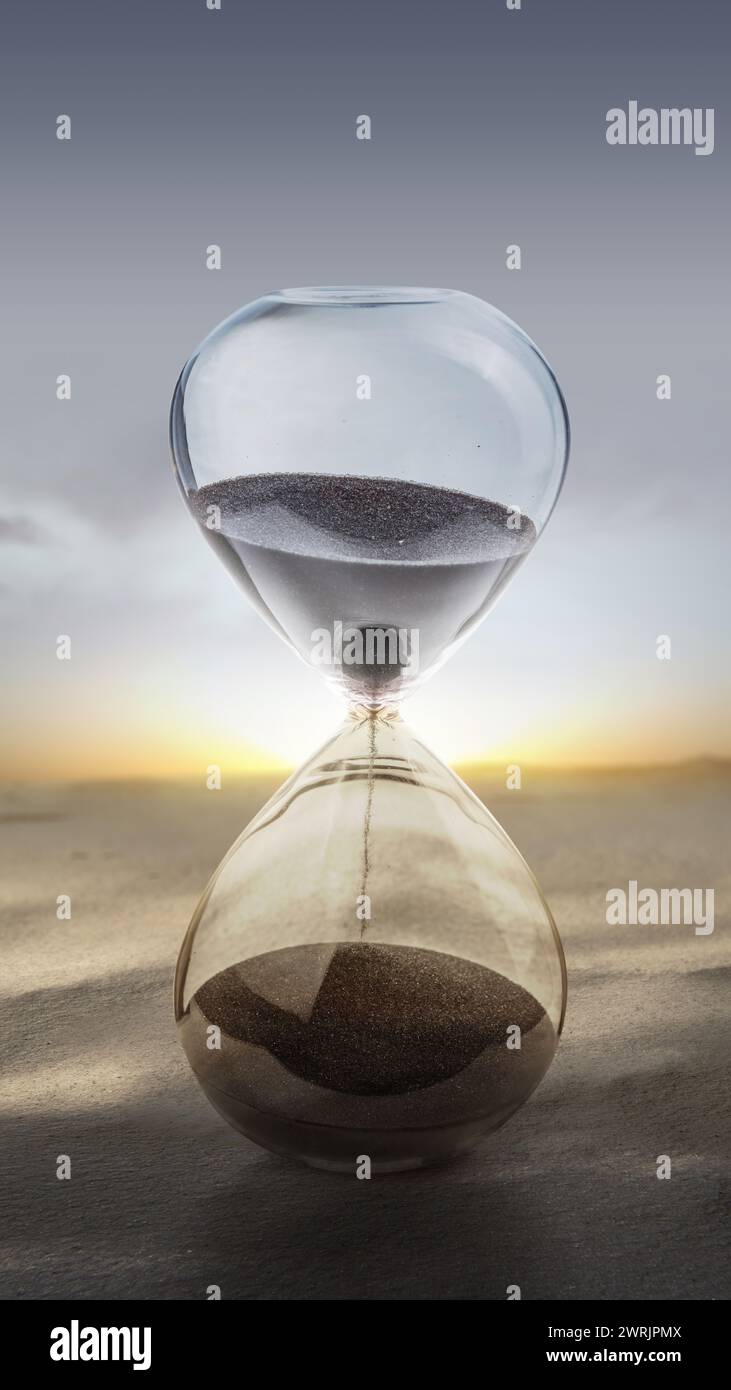 Flowing sand in the hourglass with a dramatic sky background. Time ...