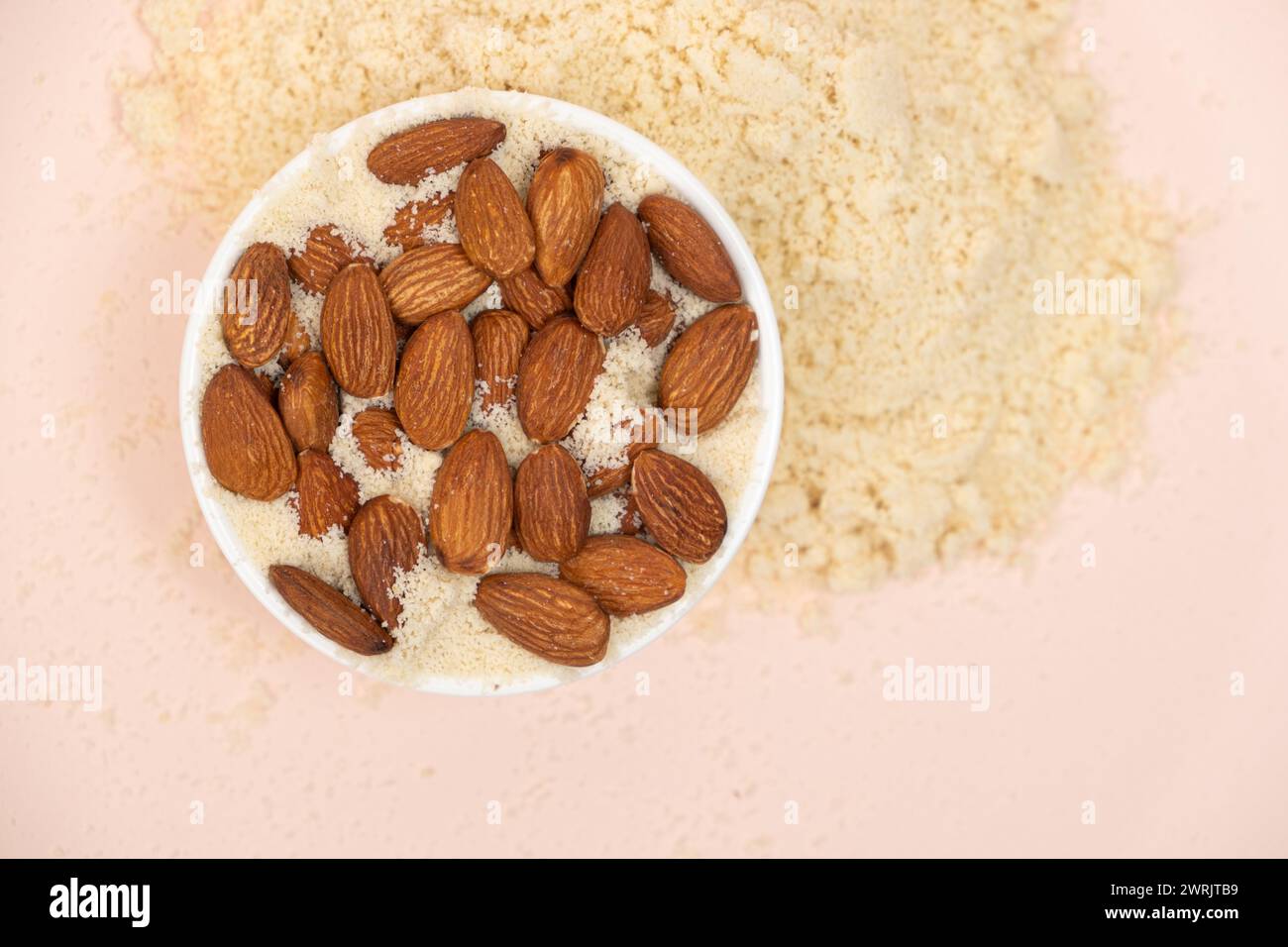 Almond flour and almonds on a pink background top view Stock Photo - Alamy
