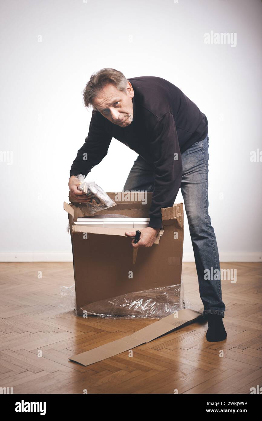 Man unpacking paper box with set of three laminated wood drawers Stock ...