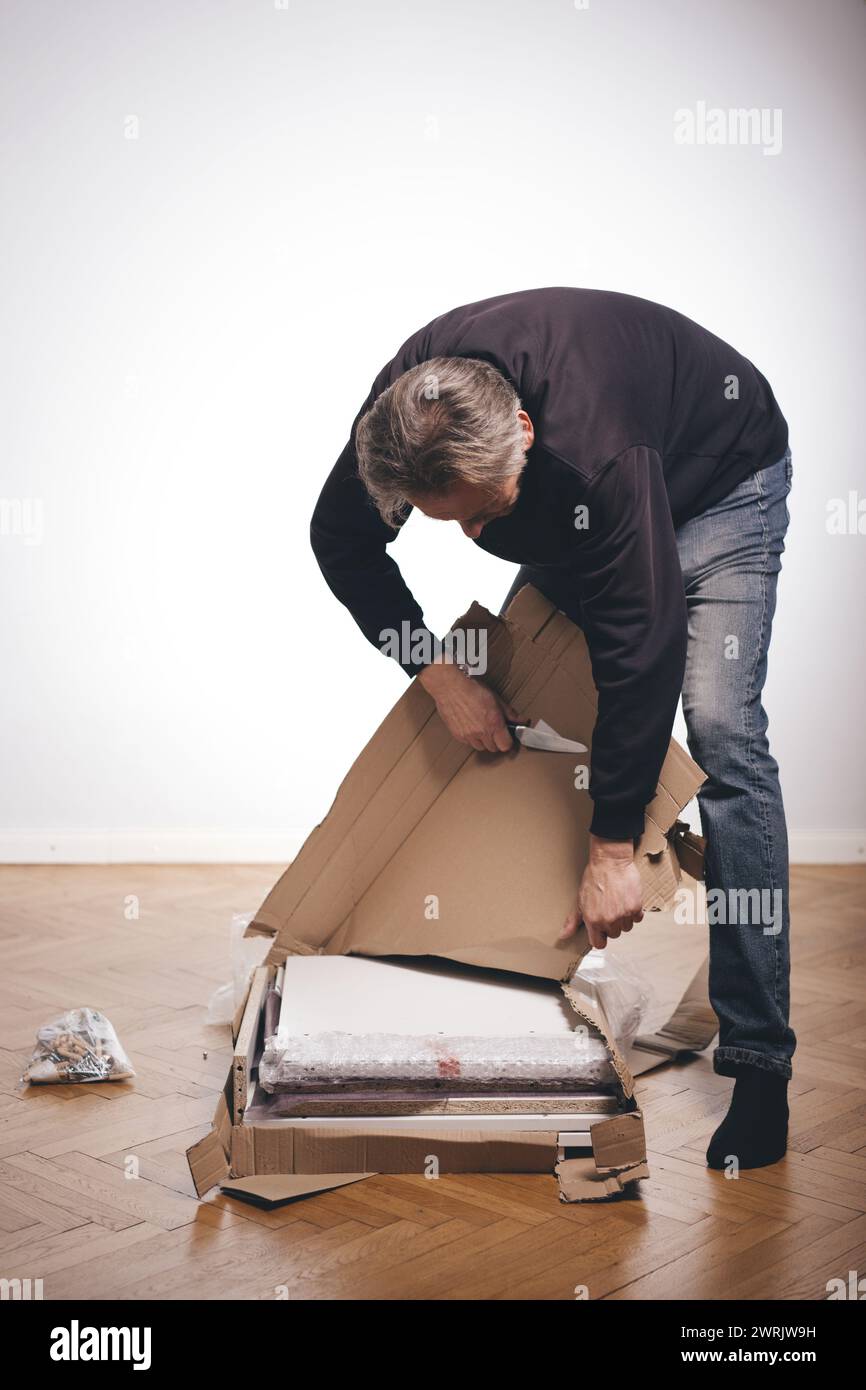 Man unpacking paper box with set of three laminated wood drawers Stock ...