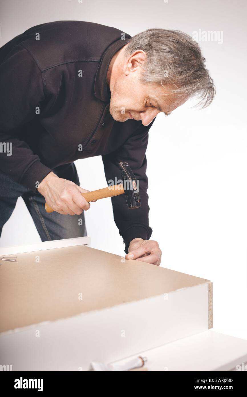 Man assembling set of three laminated wooden drawers Stock Photo - Alamy