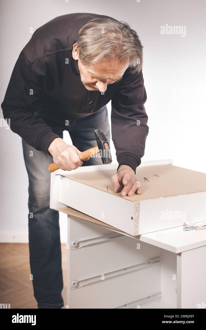 Man assembling set of three laminated wooden drawers Stock Photo - Alamy