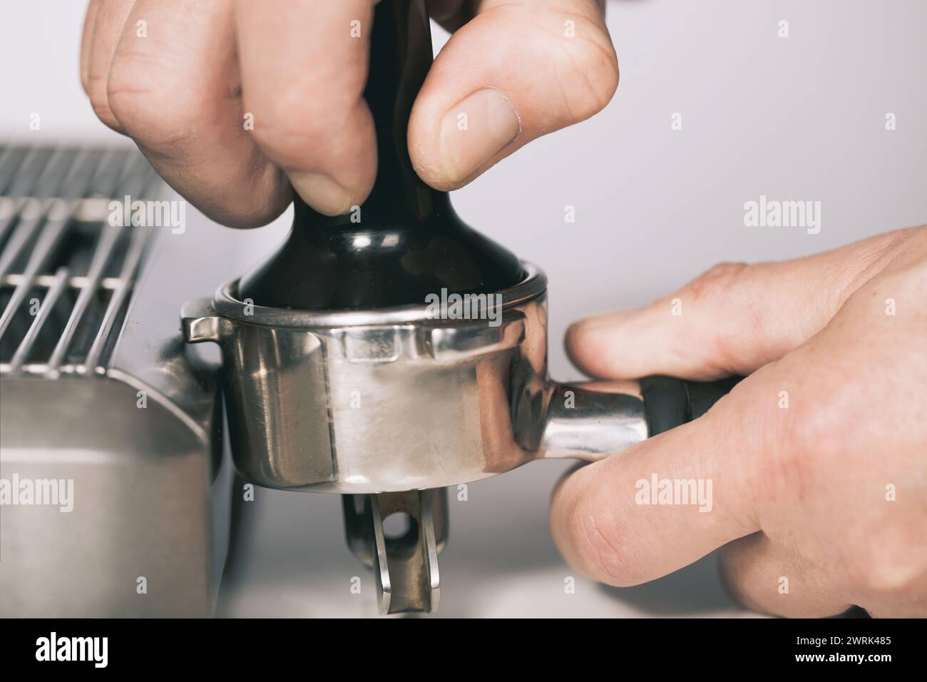 Pressing ground coffee in handle for extracting in espresso machine ...