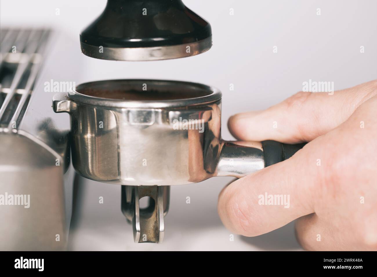 Pressing ground coffee in handle for extracting in espresso machine ...