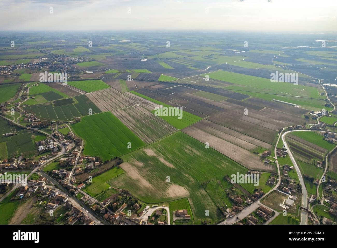 The aerial view shows a vast expanse of green field in the Pianura ...