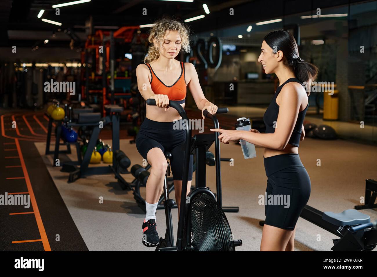 joyous athletic female coach helping her beautiful client to use cross ...