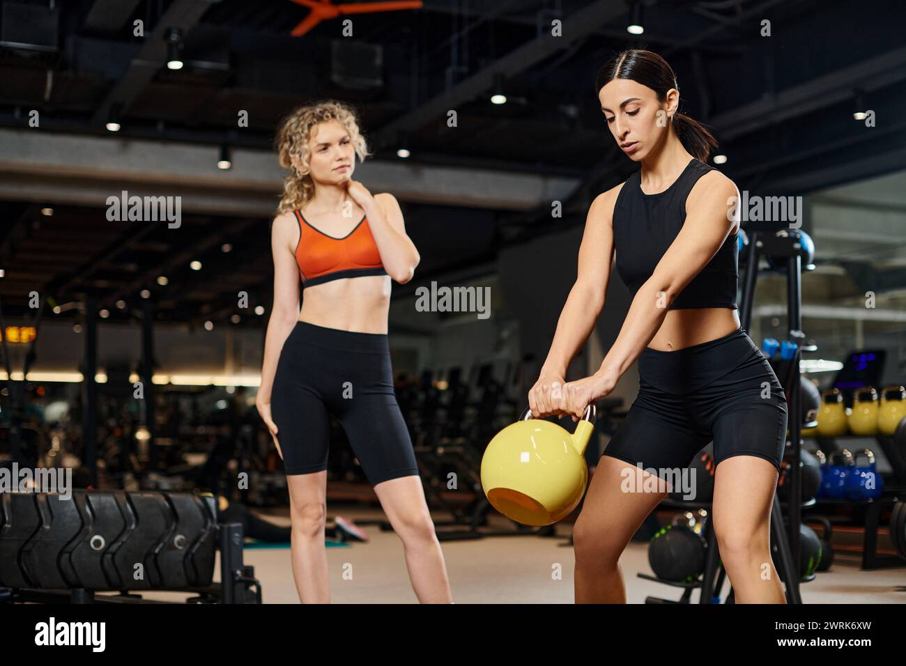 athletic attractive coach in comfy sportwear watching her client using ...