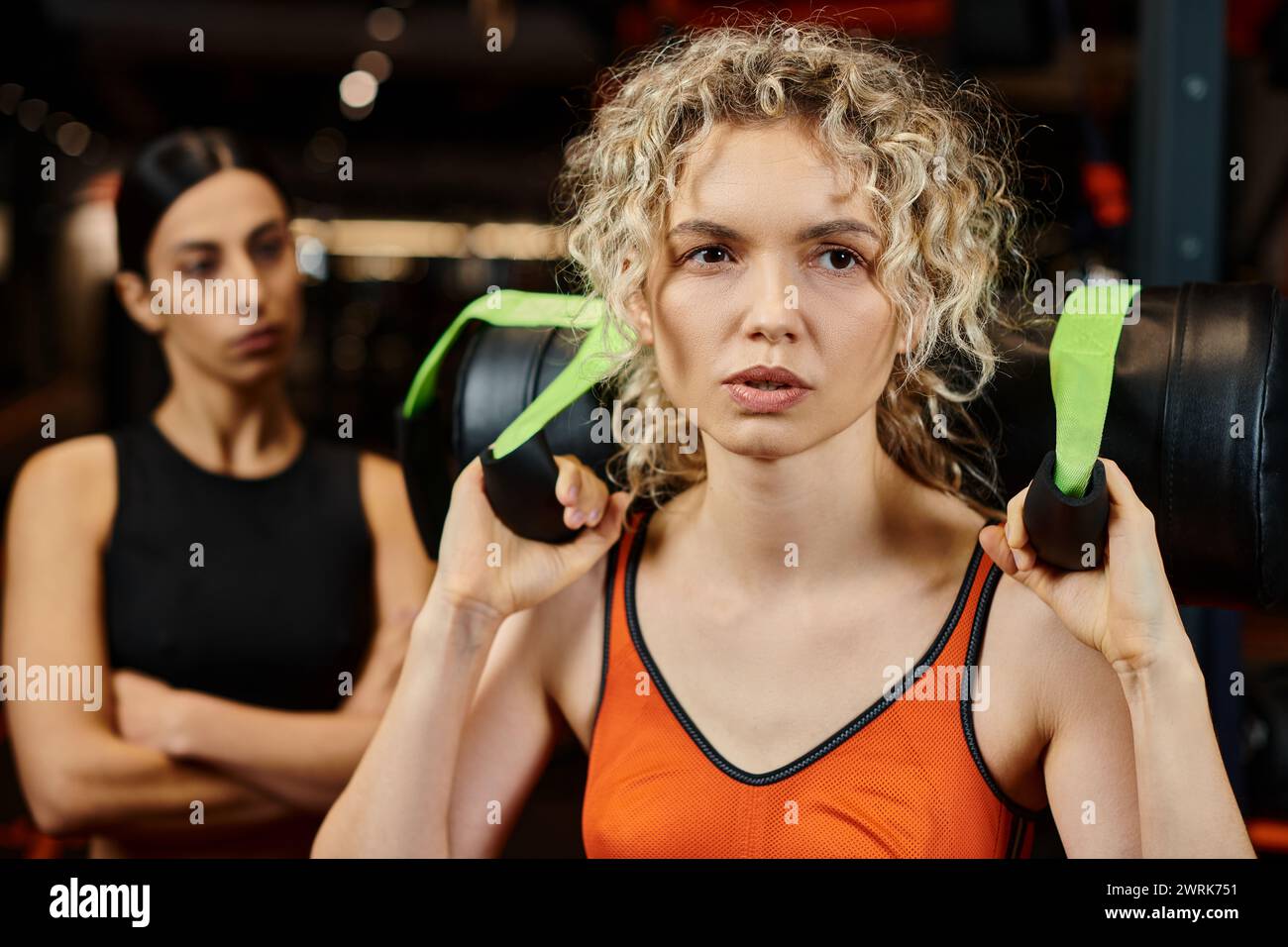 focus on blonde attractive woman exercising with power bag with her ...