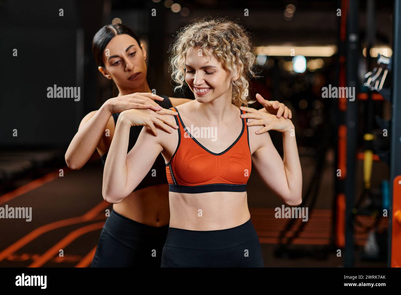 athletic cheerful female coach helping her blonde jolly client to ...