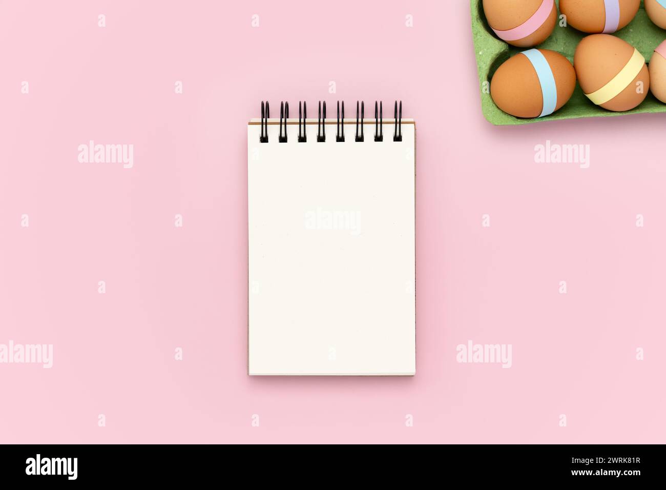 Blank spiral notebook notepad on pink background with green egg carton ...