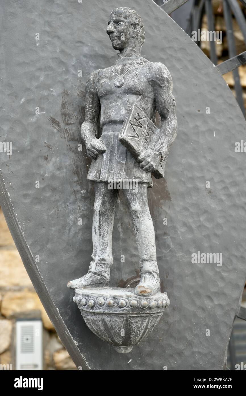 Tiny metal statue of a man holding a book on gates at castle hill, Buda ...