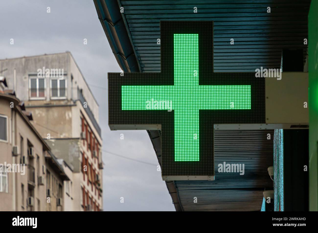 Shiny illuminated glowing pharmacy cross sign on building facade ...