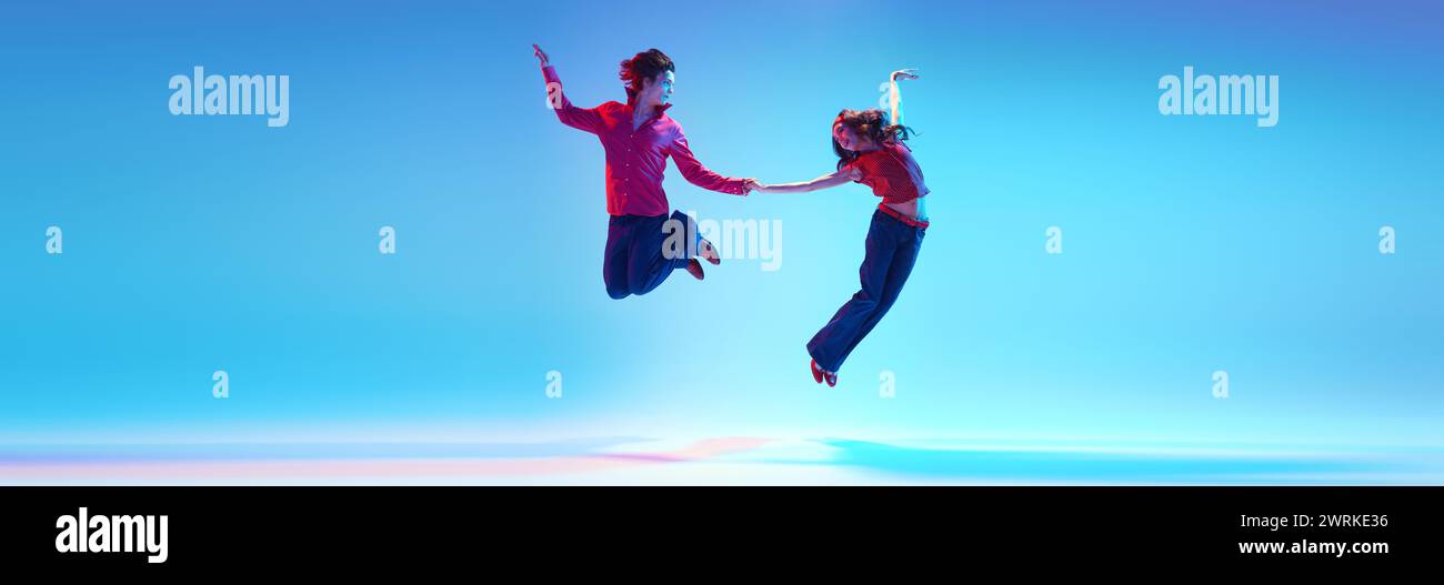 Dynamic image of young couple dancing retro dance, jumping against blue ...