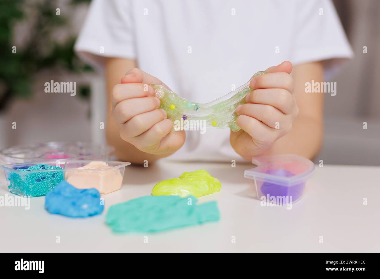 Girl playing with different colors and textures slime at table Stock ...