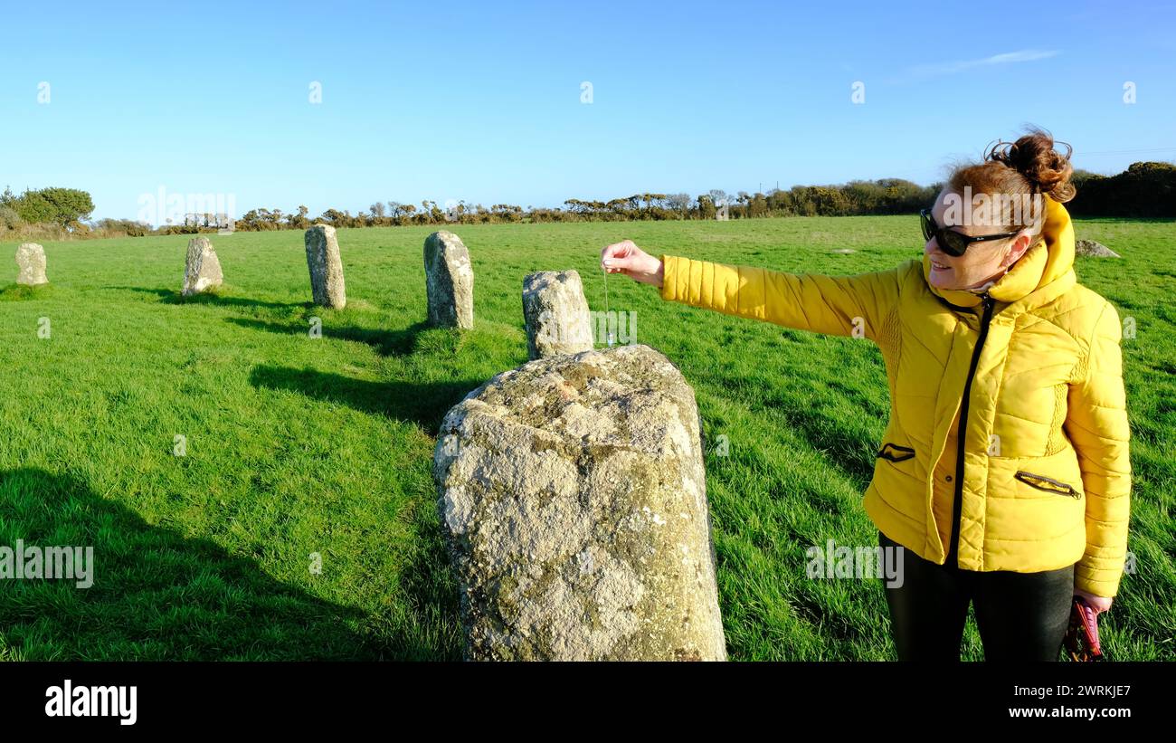 Female dowsing a standing stone using a crystal pendulum at the Merry ...