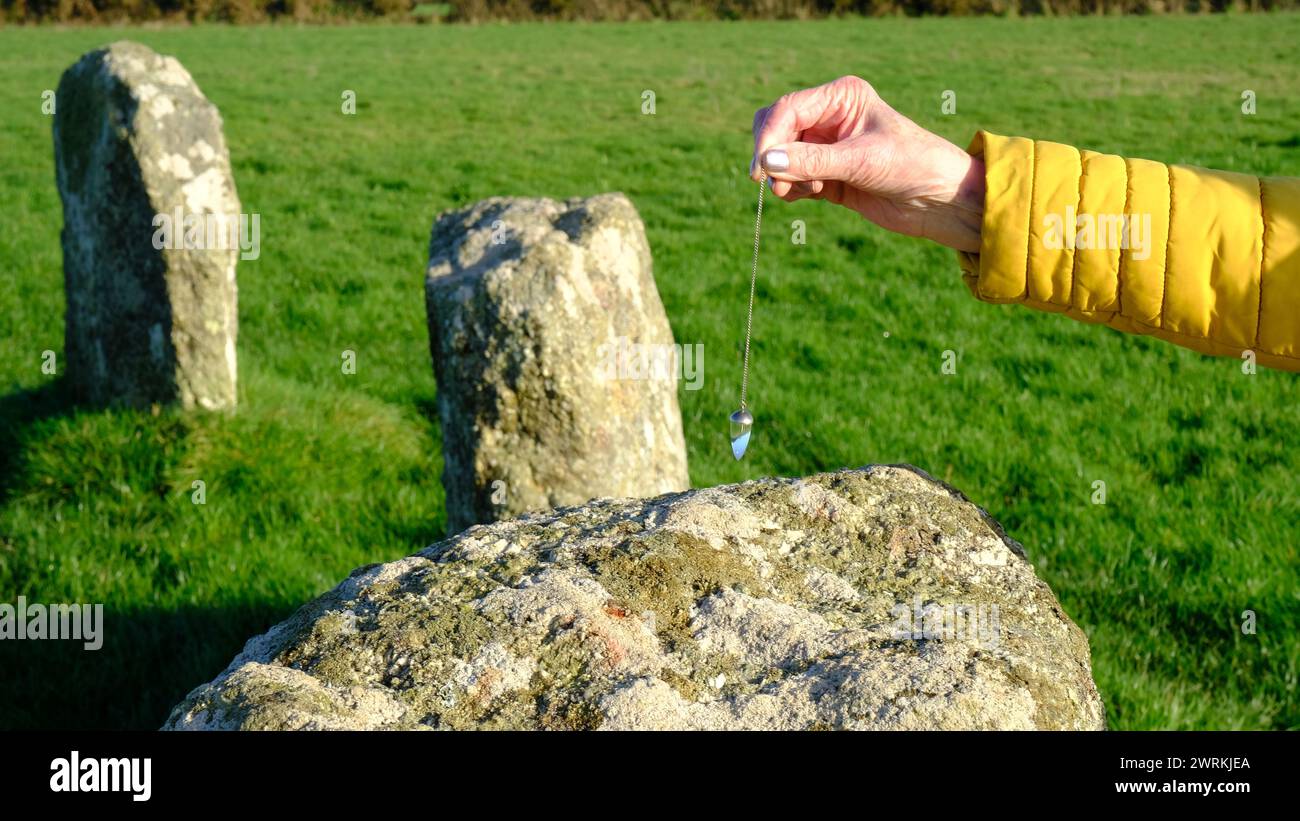 Female dowsing a standing stone using a crystal pendulum at the Merry ...