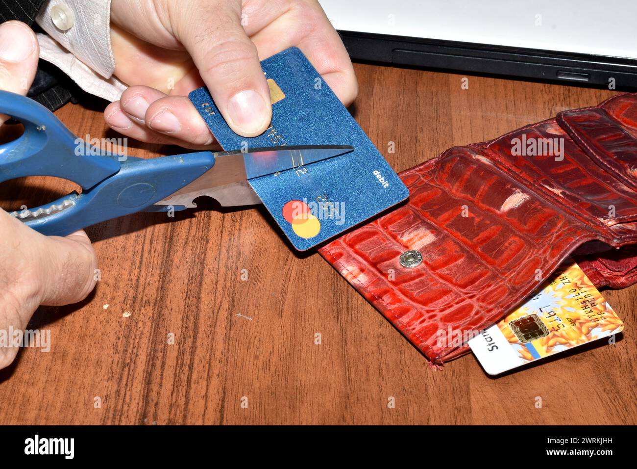 The picture shows male hands holding scissors and a plastic bank card ...