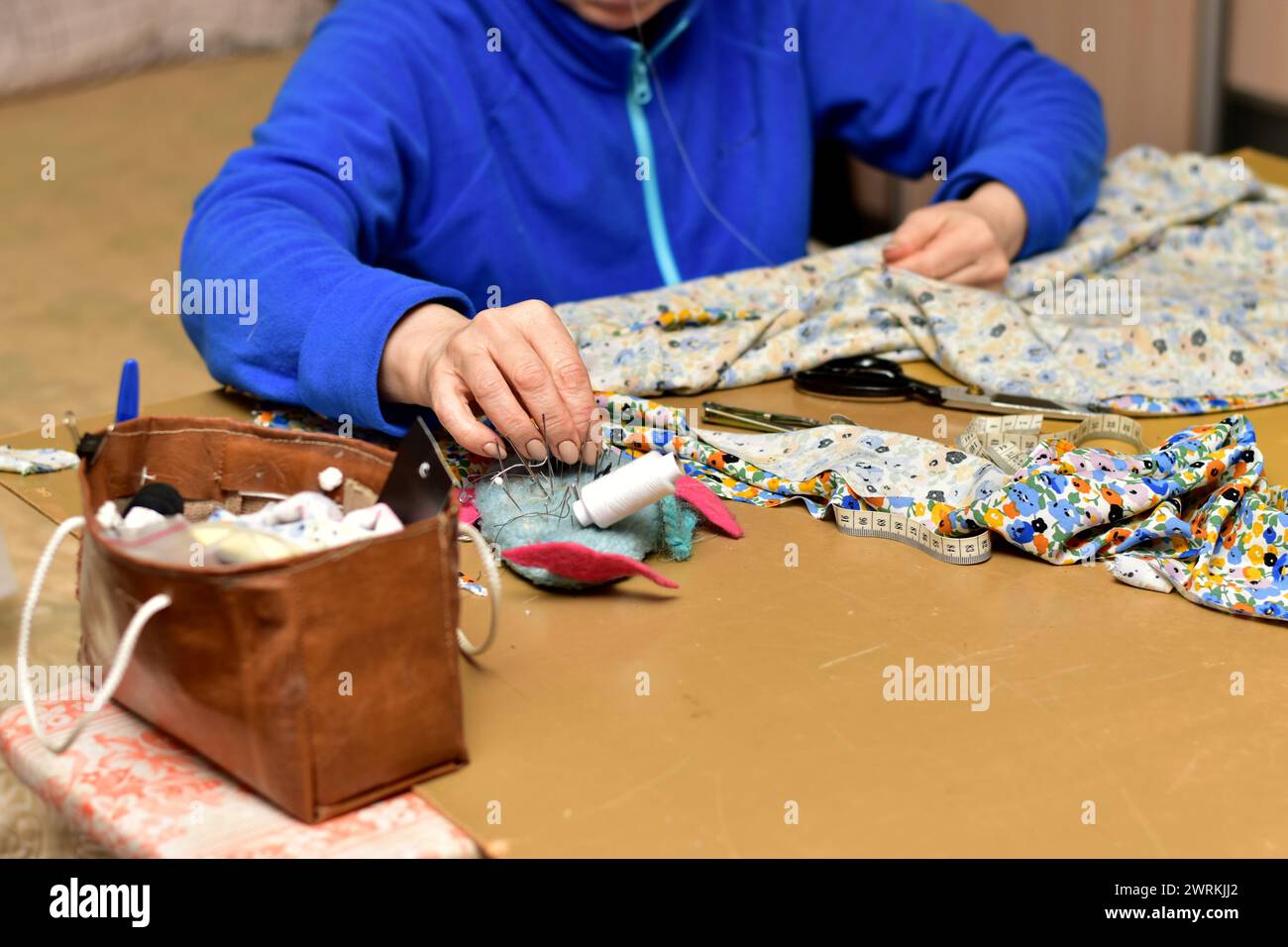 The picture shows a seamstress who has laid out the fabric on the table ...