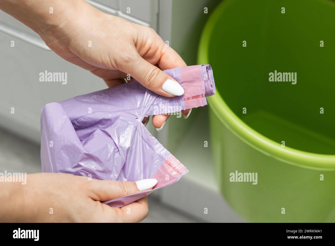 a man changes a garbage bag in a bucket. woman tearing off a trash bag ...