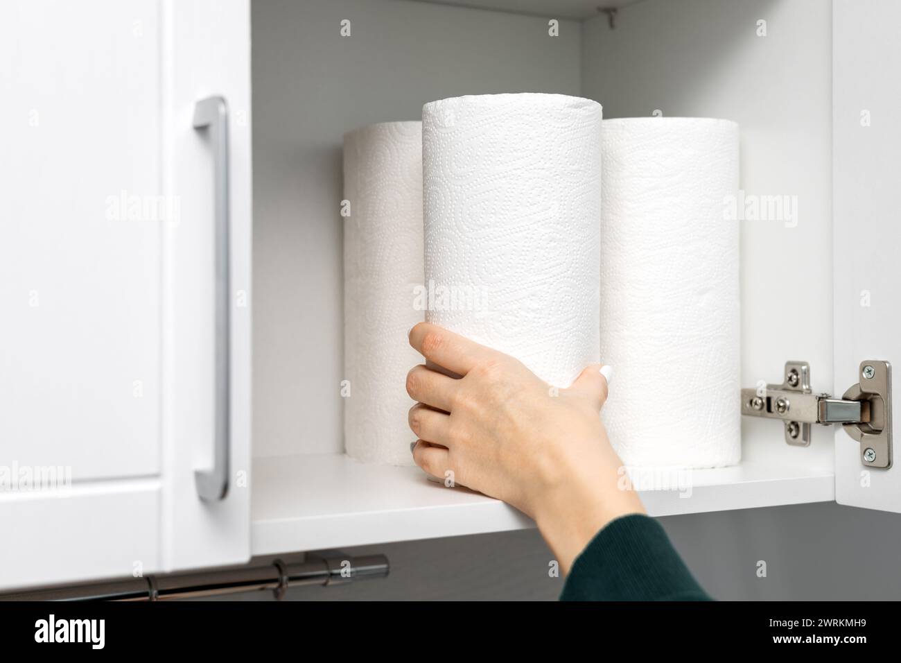housewife takes out a roll of paper towel from the kitchen cabinet ...
