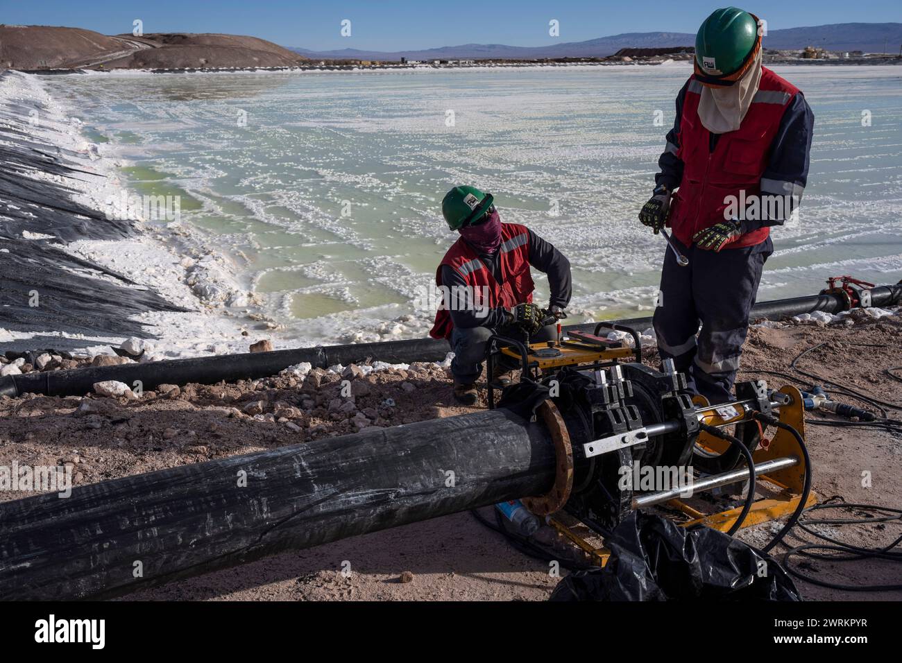 Workers perform maintenance at the pools where brine is evaporated at ...
