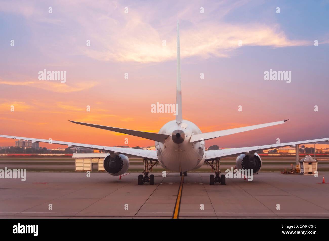 Passenger plane parked in the air harbor during dawn sky, rear view ...
