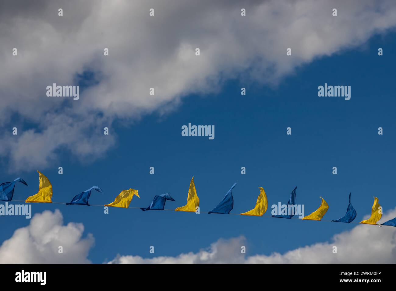 Yellow and blue triangular festival flags on sky background with white ...