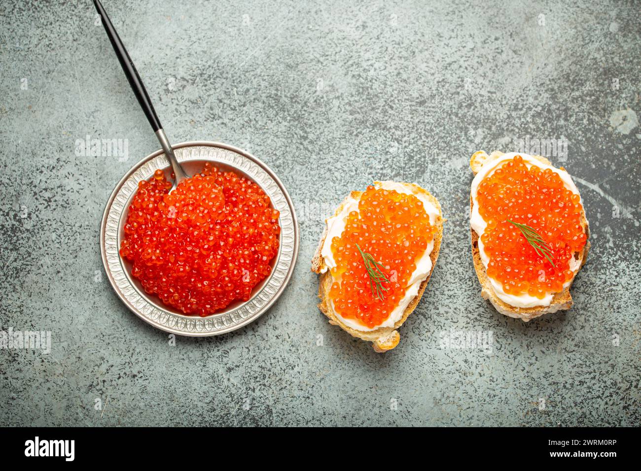 Small metal plate with red salmon caviar and two caviar toasts on grey ...