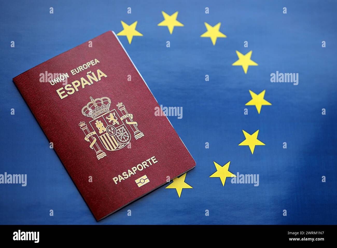 Red Spanish passport of European Union on blue flag background close up ...