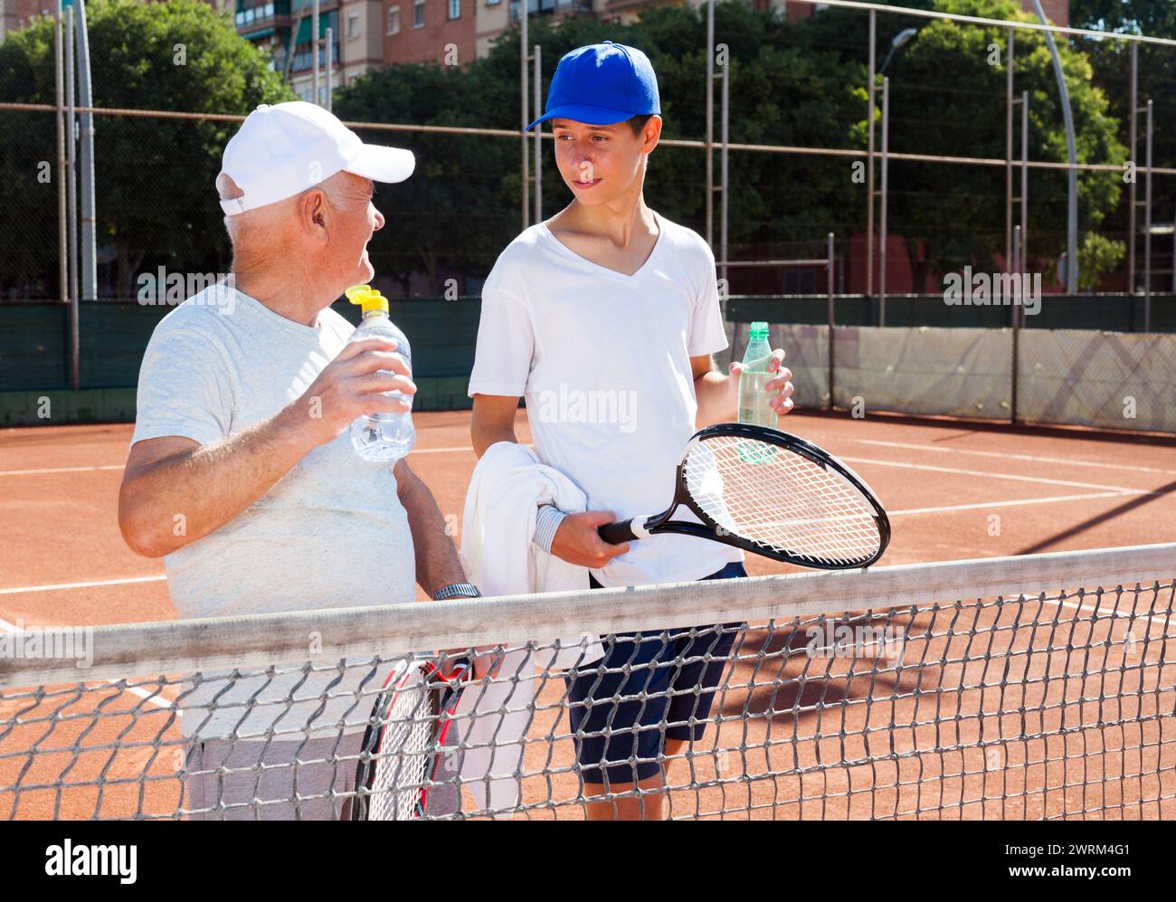 Tennis players of different generations drink water on tennis court ...